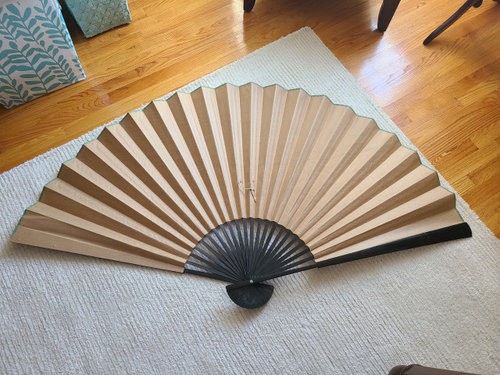 How do I securely mount a large, folding paper fan on the wall?