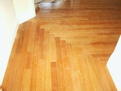 How should hardwood in an L-shaped hall be installed?