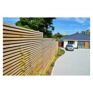 Contemporary driveway on a slope fenced in using Western Red Cedar ...