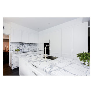 Kitchen with white shaker profile cabinets and marble benchtops ...