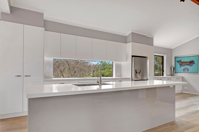 Spacious modern kitchen with island benchtop, flat panels and overhead ...