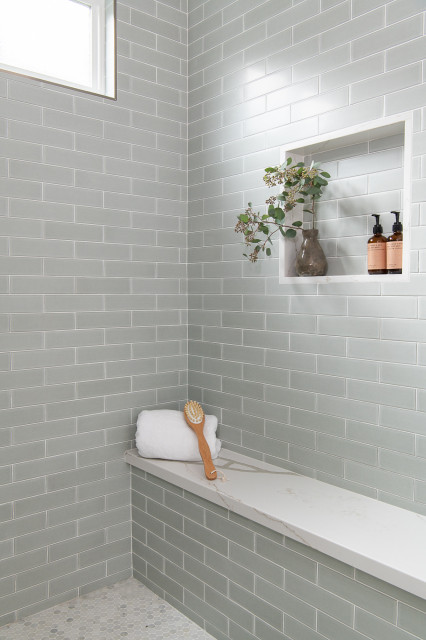 The shower features a shampoo niche, a sitting bench and a shower curb ...