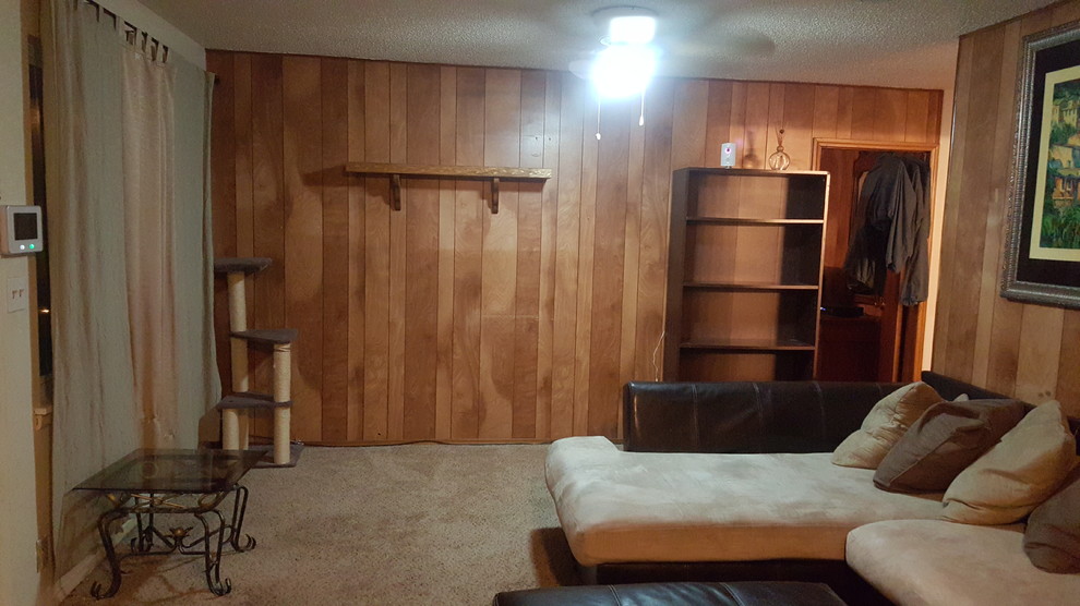 Long narrow living room with wood paneling and 3 doorways
