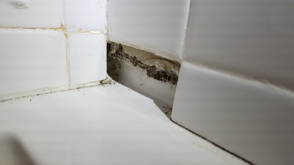 How do I fill gap behind a shower wall and title to flush mount?