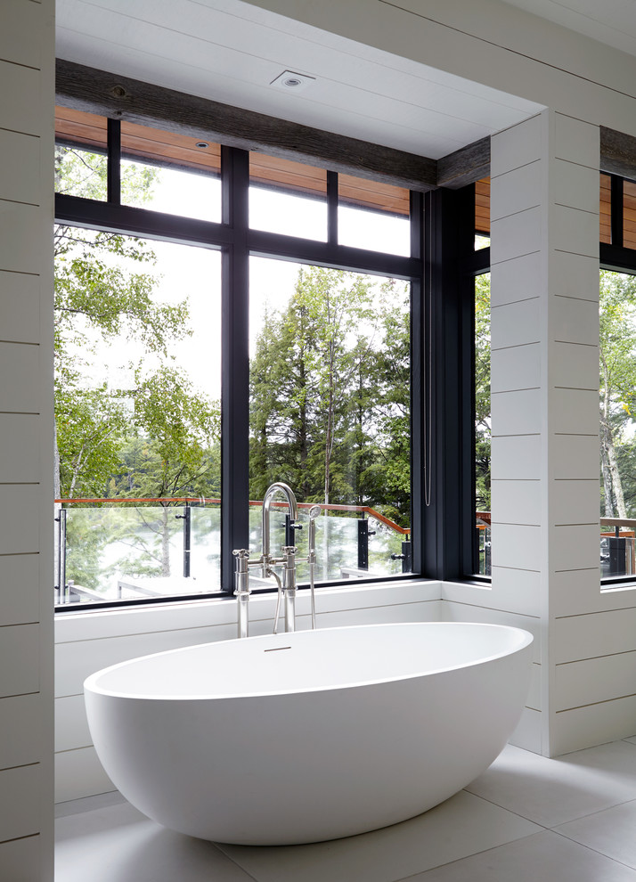A soaker tub surrounded by windows that look out to trees and outdoor ...