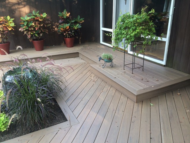 Timbertech Pecan deck built around tree, flower bed, and water feature ...