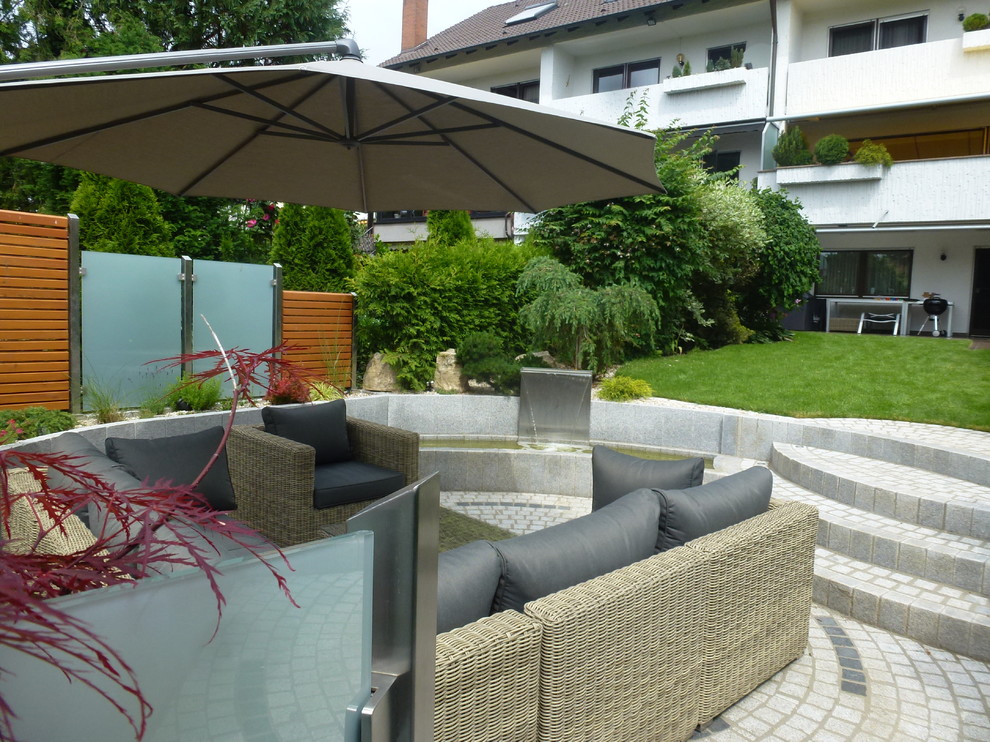 Gepflasterter Sitzplatz mit Glas-Sichtschutzwänden und ...