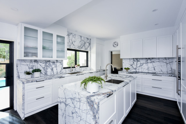 Kitchen with white shaker profile cabinets and marble benchtops ...