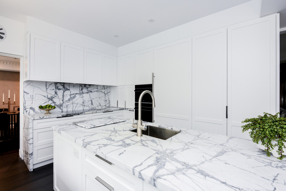 Kitchen with white shaker profile cabinets and marble benchtops ...