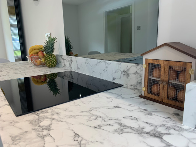 Marble look laminate worktop, induction hob and mirrored splashback ...