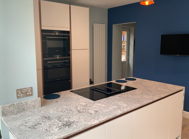 Matt white handleless kitchen with quartz worktops and copper finger ...