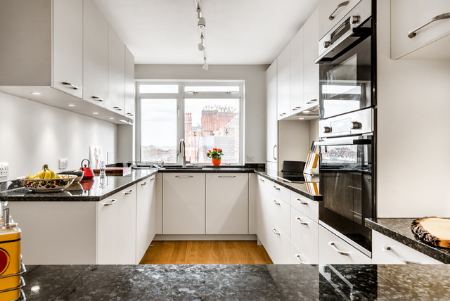 Matt white kitchen with stainless steel handles and granite worktop ...