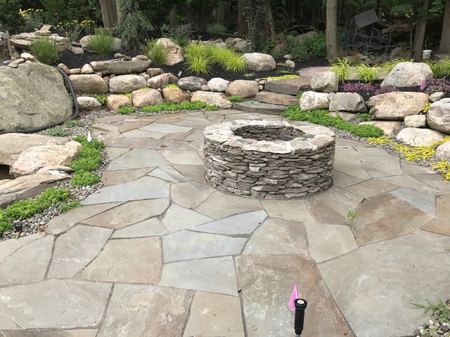 Backyard Oasis with a fieldstone fire pit and natural rock - Garden ...
