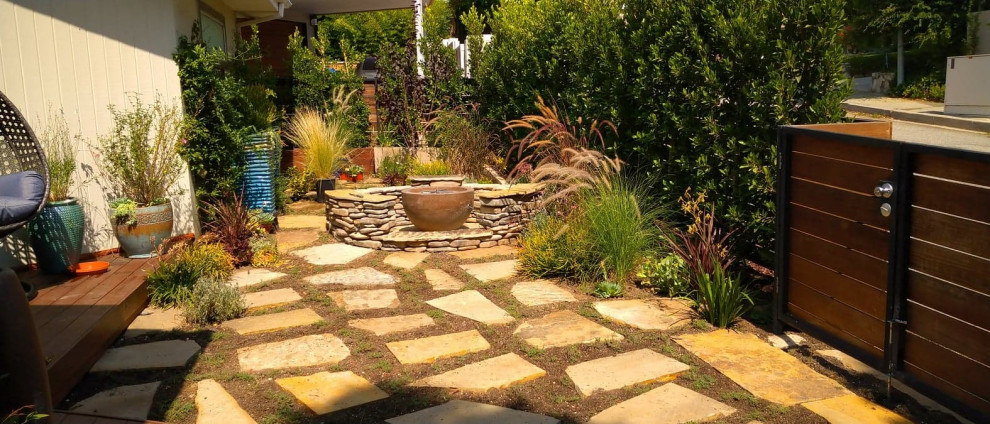 Courtyard with lush look - wood deck and stone fire pit seating area ...