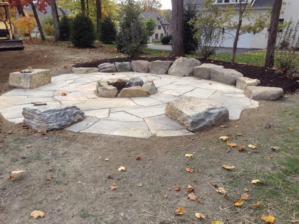Large fire pit area with boulder tables and rock wall seating. Custom ...