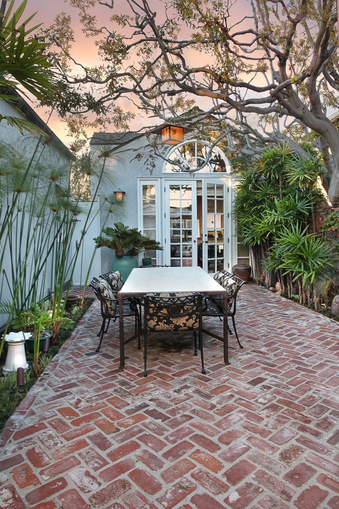 brick atrium with outdoor dining table & tree chandelier - Eclectic ...